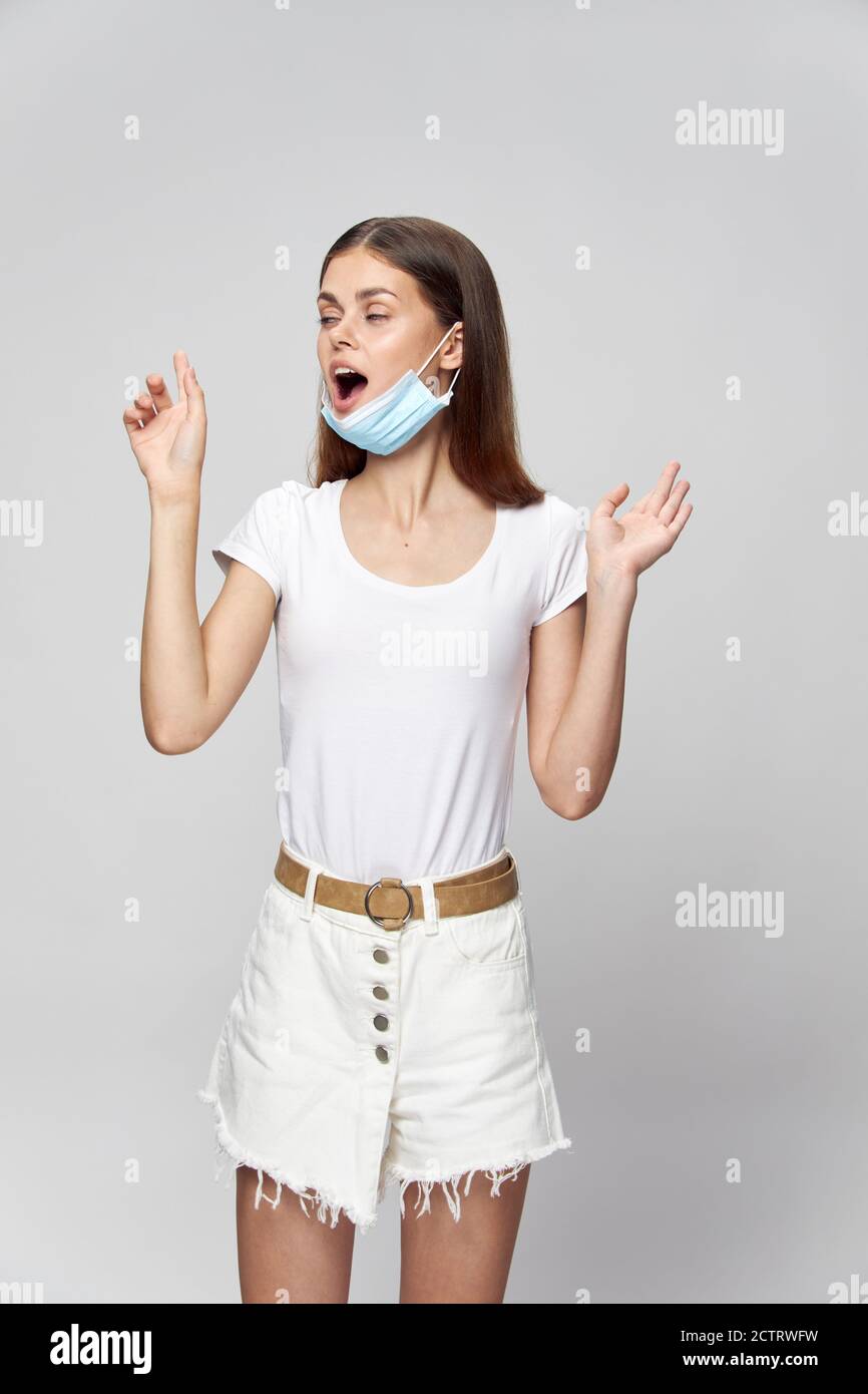 Woman with closed eyes on a gray background gestures with her hands and ...