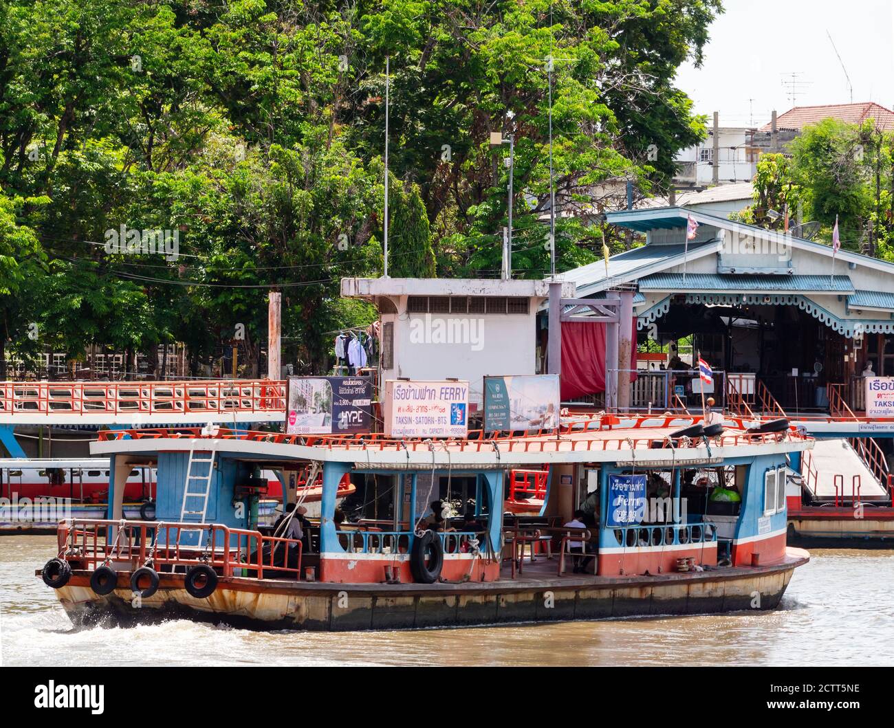 Passenger ferry crossing the Chao Phraya River under the Taksin Bridge ...