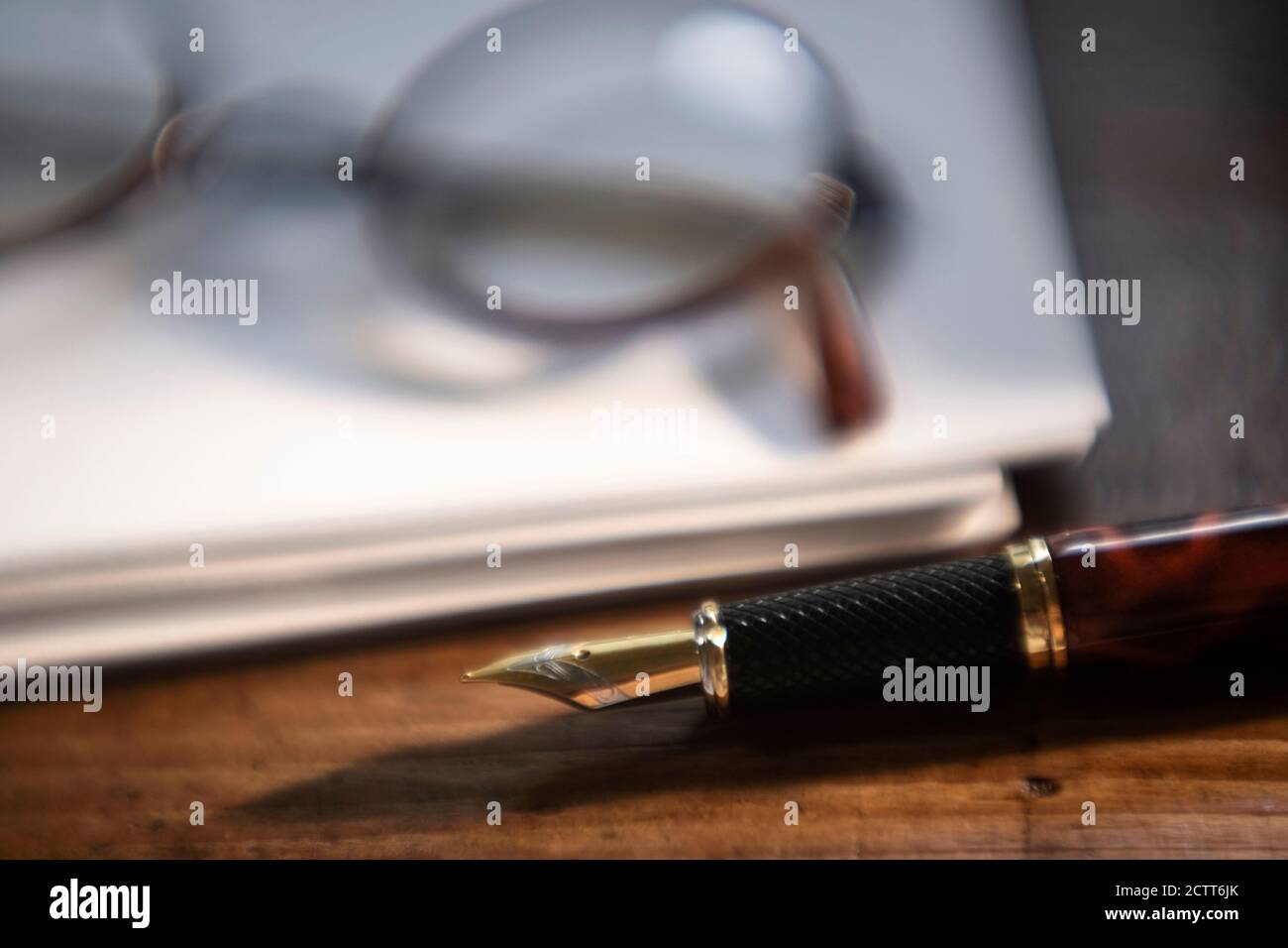 Retro eyeglasses and pen on stack of paper Stock Photo - Alamy