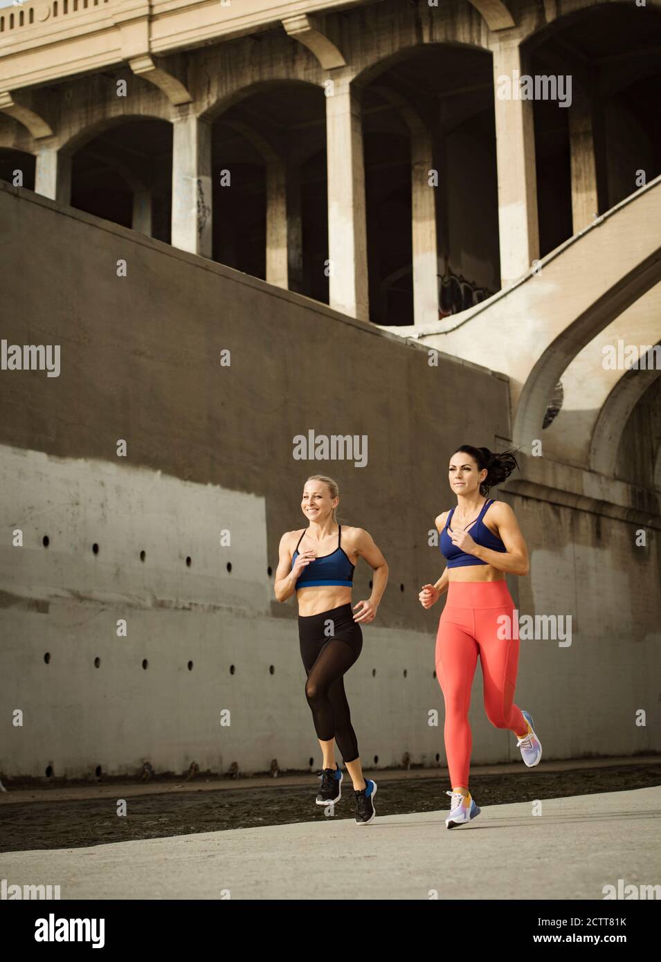 USA, California, Los Angeles, Two sporty women jogging in urban setting ...