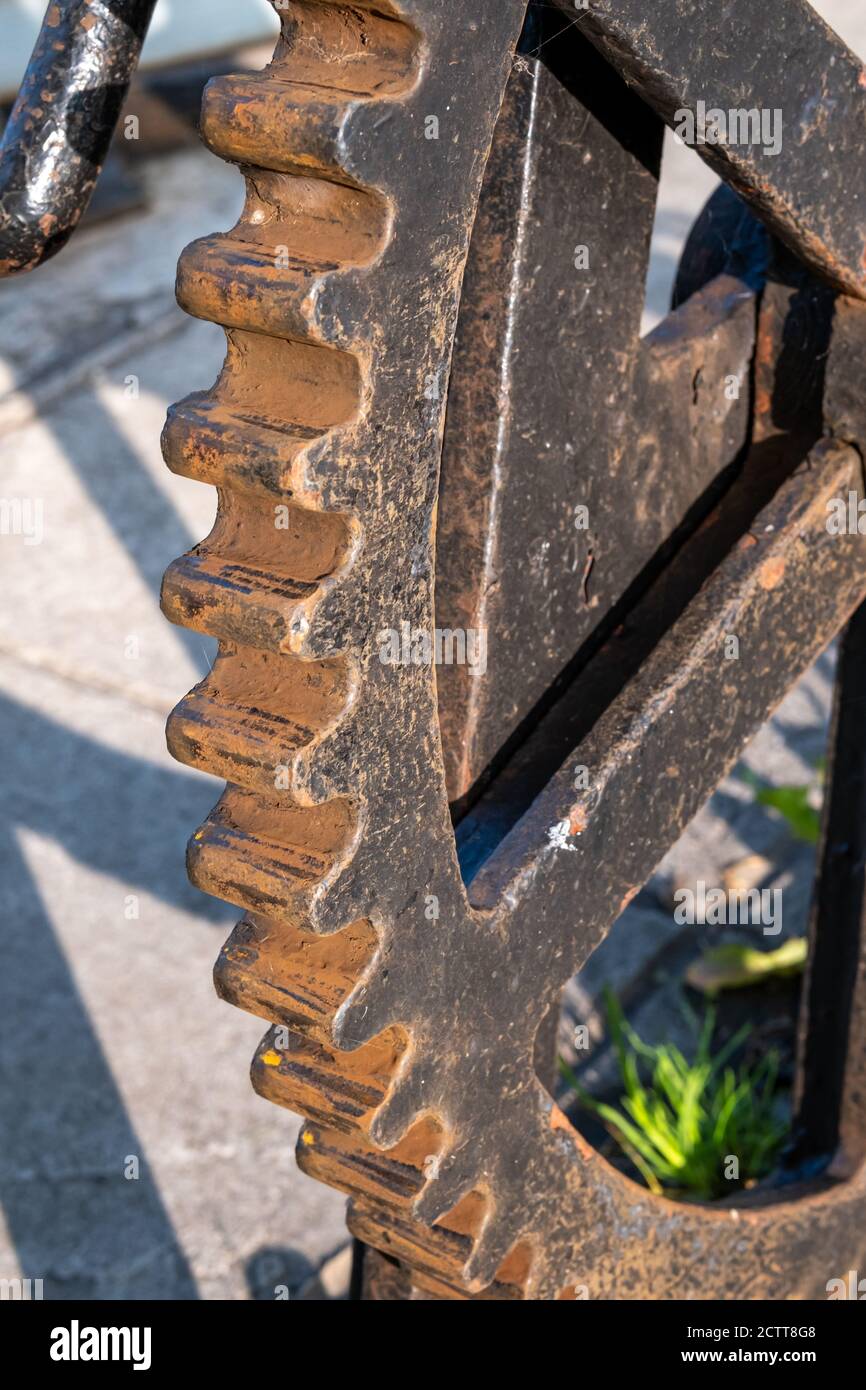 A large iron cog of a gear with rust forming on its outer prongs is ...