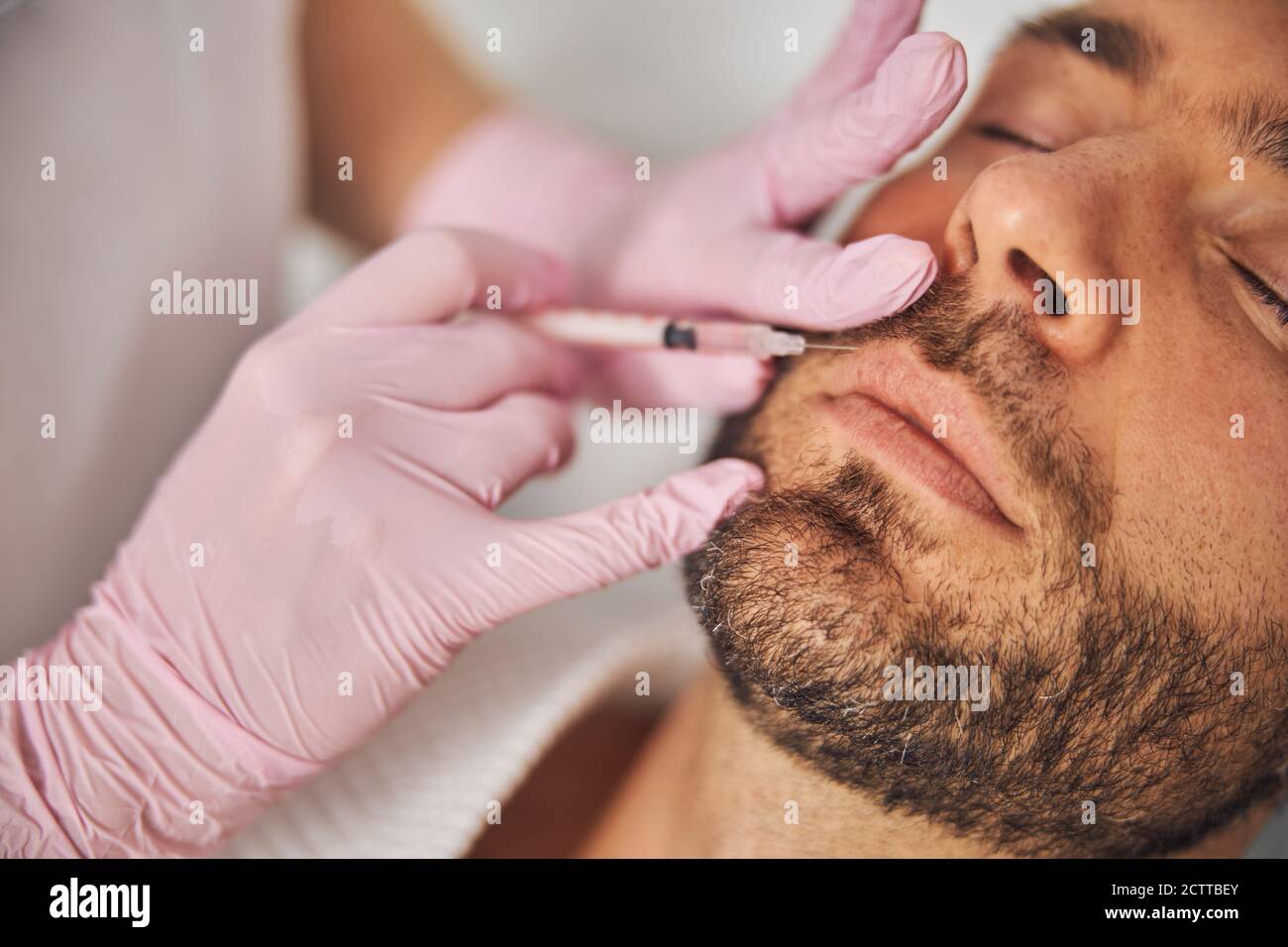Handsome young man receiving cosmetic injection at wellness center ...