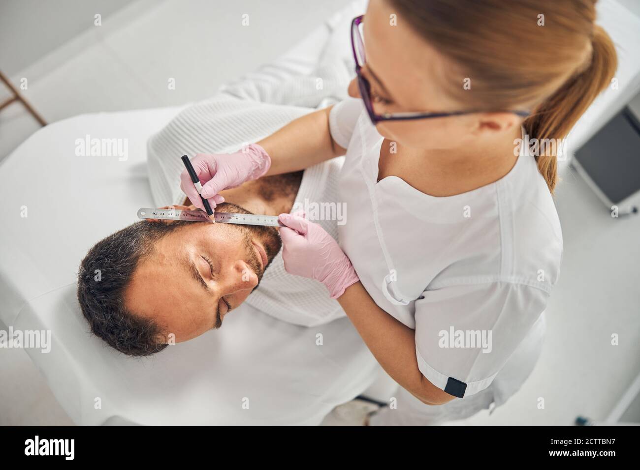 Female esthetician drawing beard cheek line on male skin Stock Photo ...