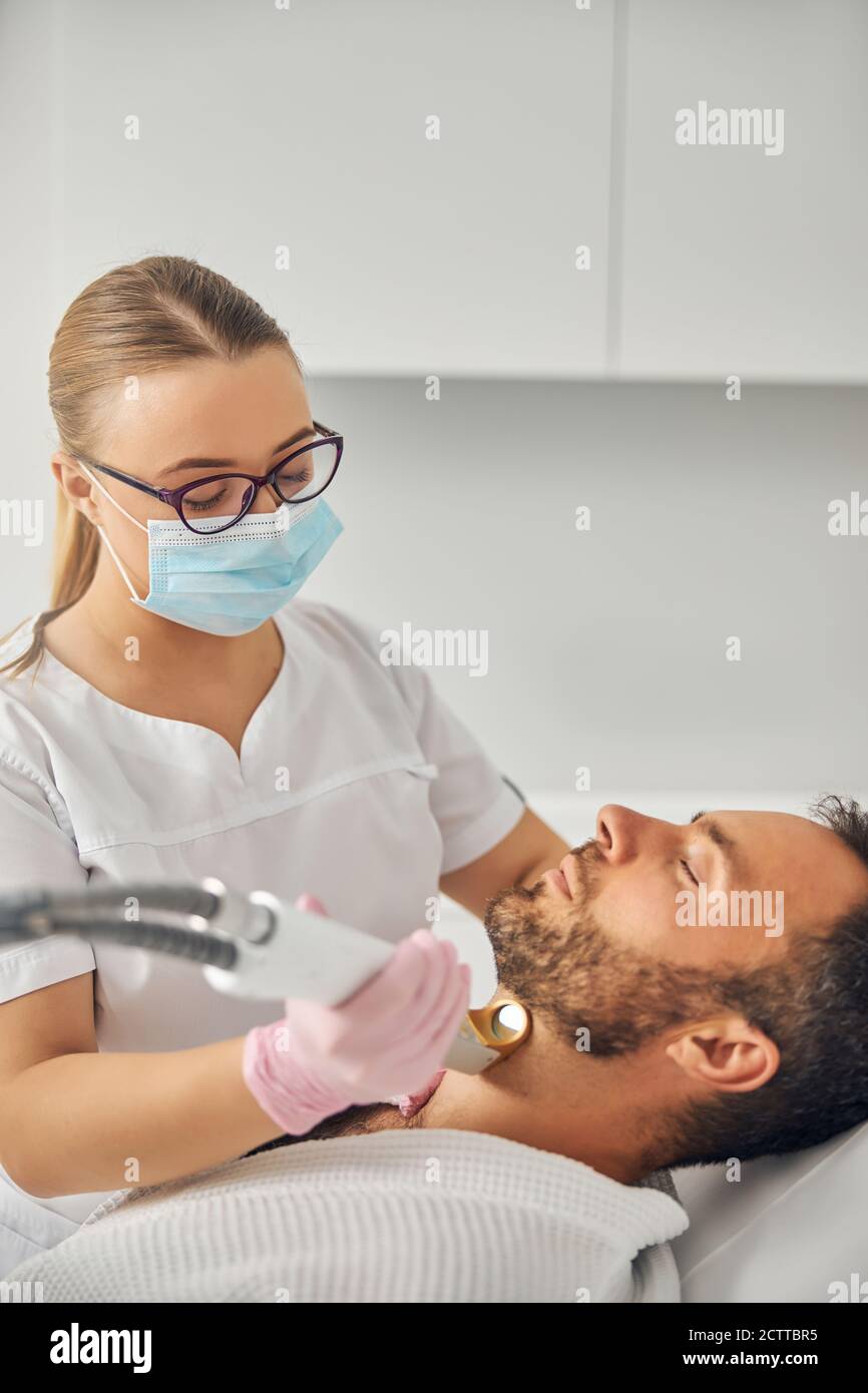 Female esthetician performing laser hair removal procedure Stock Photo ...