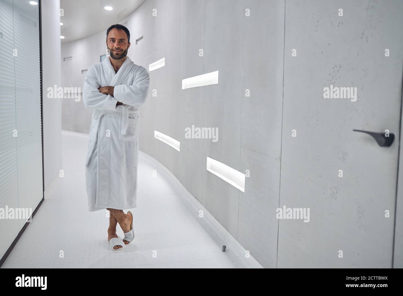 Cheerful young man standing in corridor of wellness center Stock Photo ...