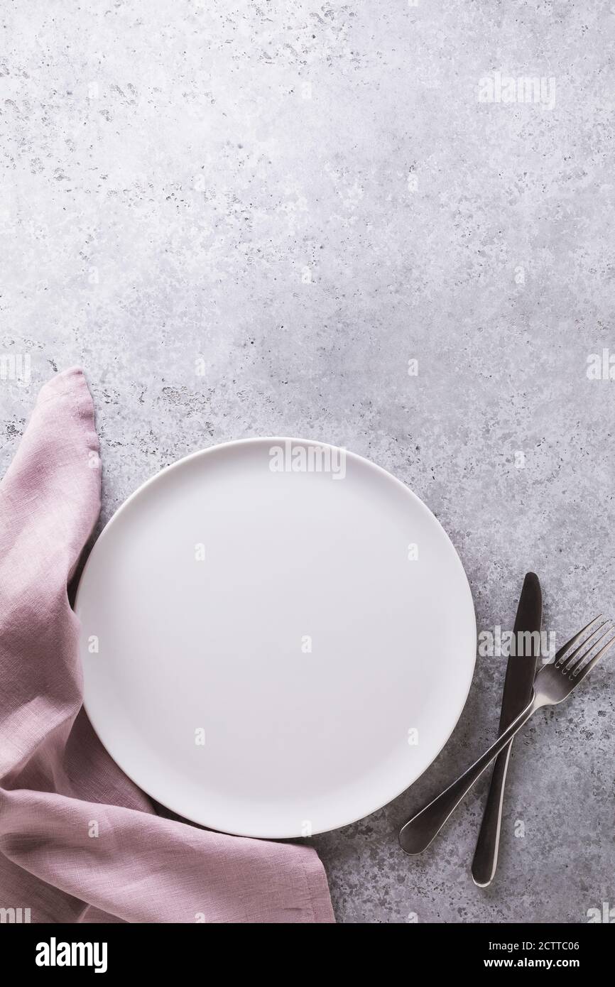 Ceramic plate, napkin and cutlery on the table with concrete texture ...