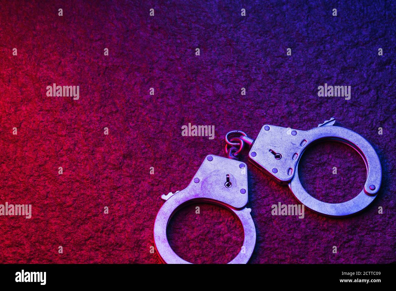 Handcuffs on a stone surface, illuminated by flashing lights of a ...