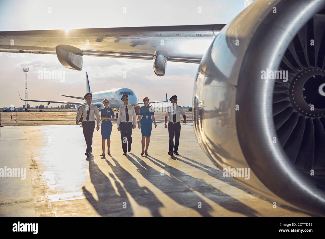 Three men pilots with two stewardesses isolated on big airplane Stock ...