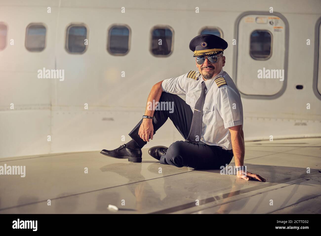 Handsome pilot in white shirt and sunglasses posing at the photo camera ...