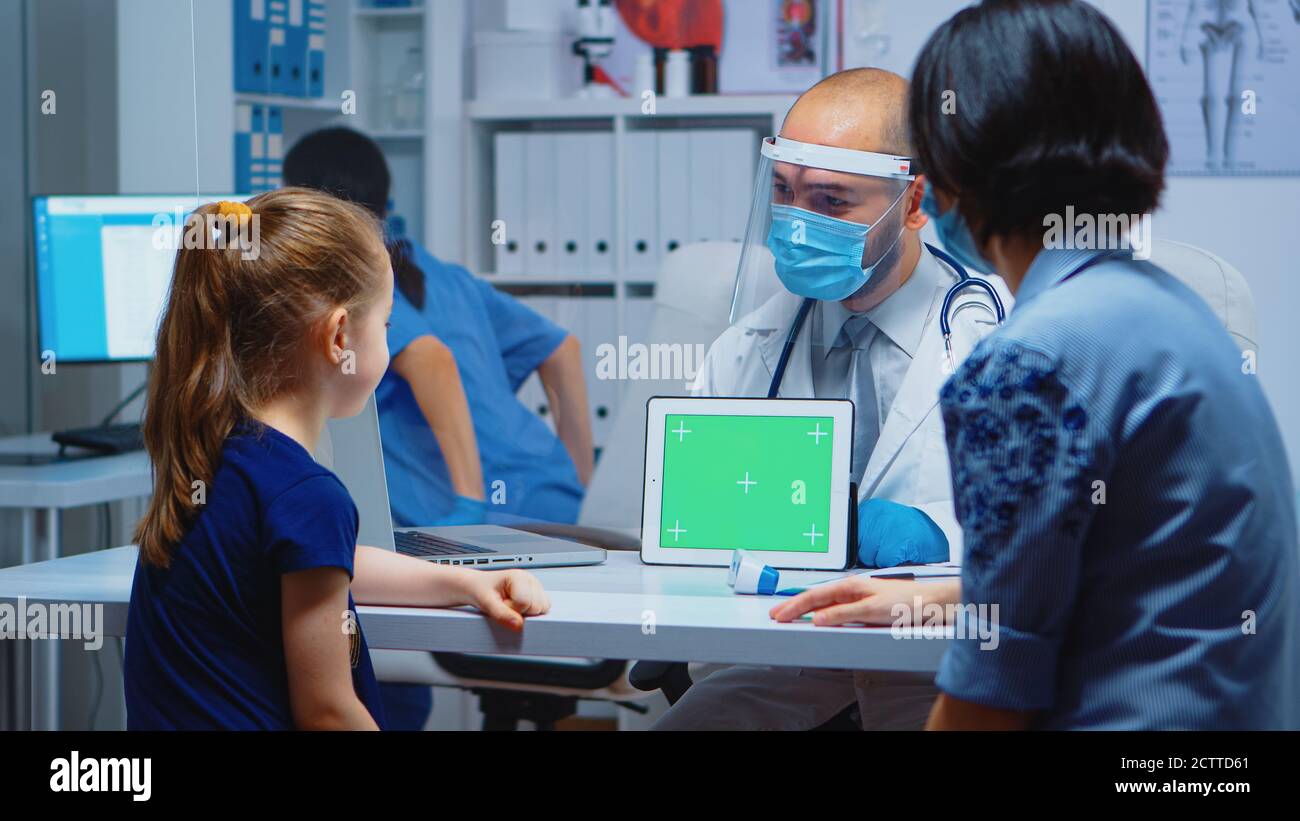Doctor holding green screen tablet in medical office sitting on the ...