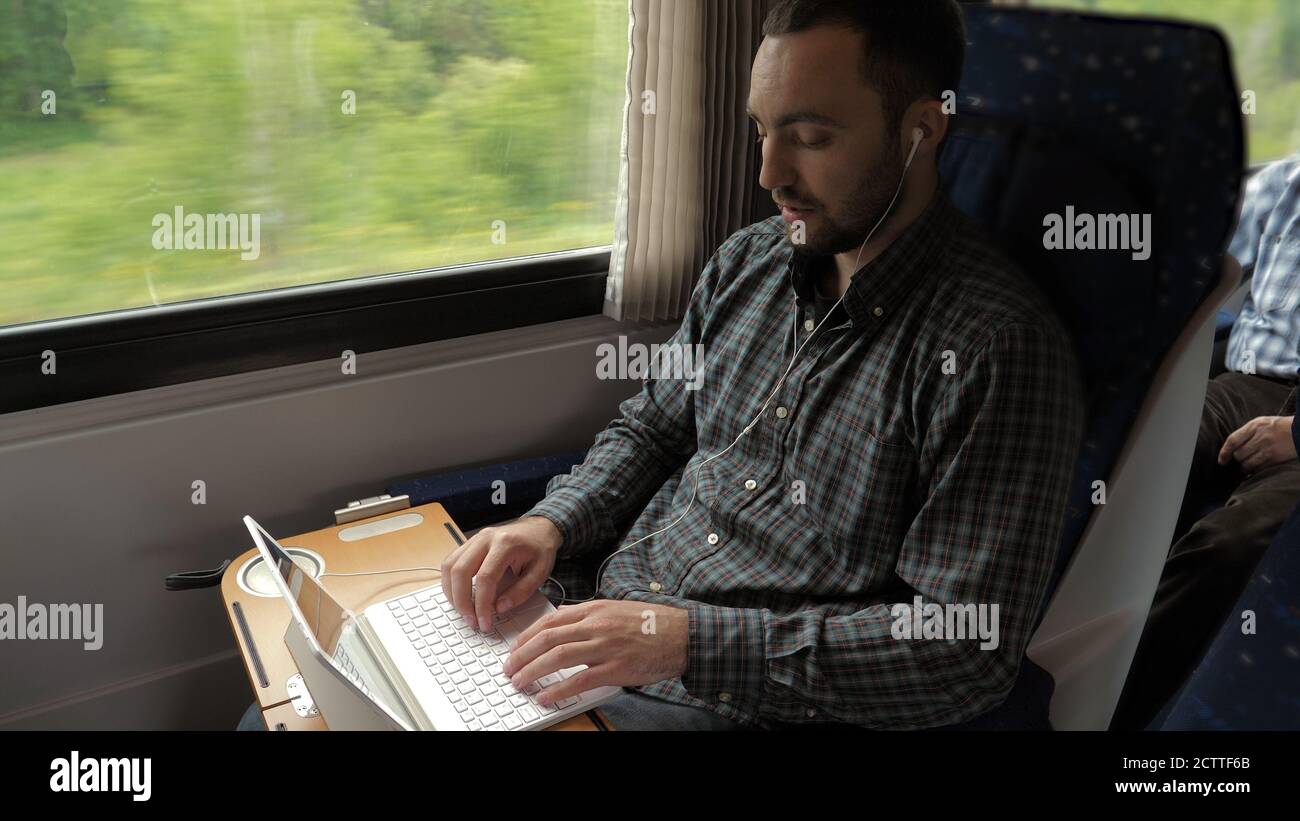 Creative man designer working on his laptop computer in a train Stock ...