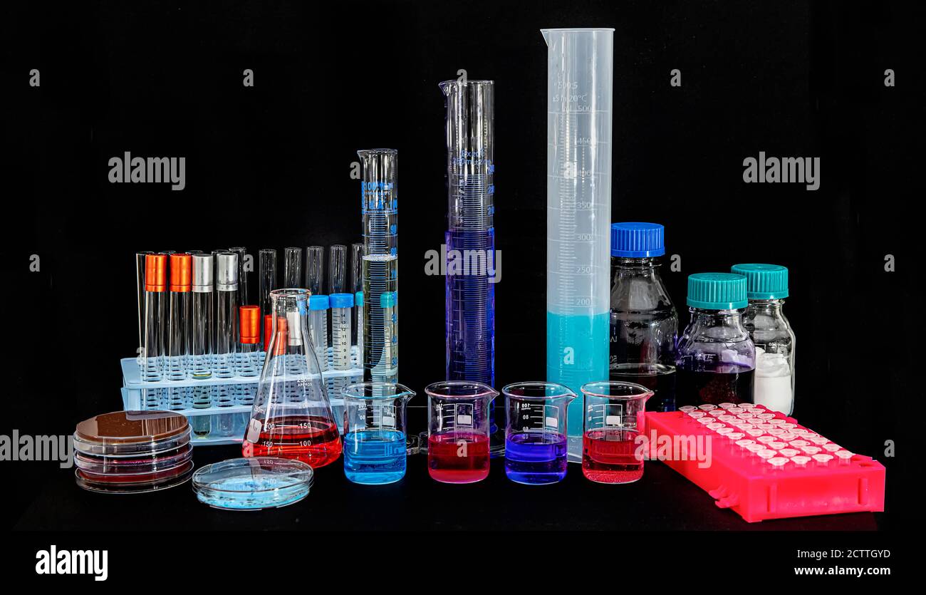 Chemical laboratory glassware with various colored liquids on table ...