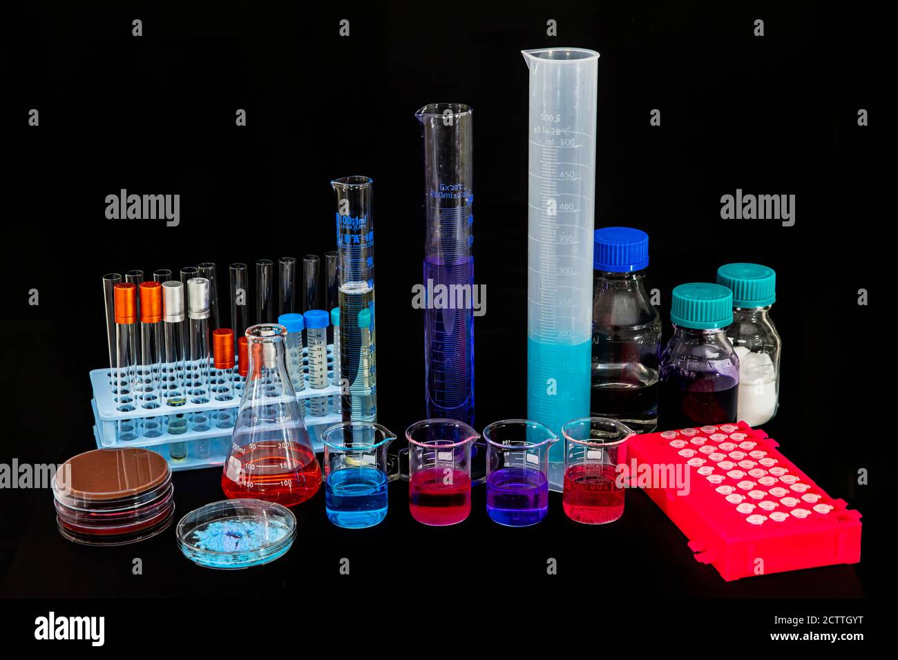 Chemical laboratory glassware with various colored liquids on table ...