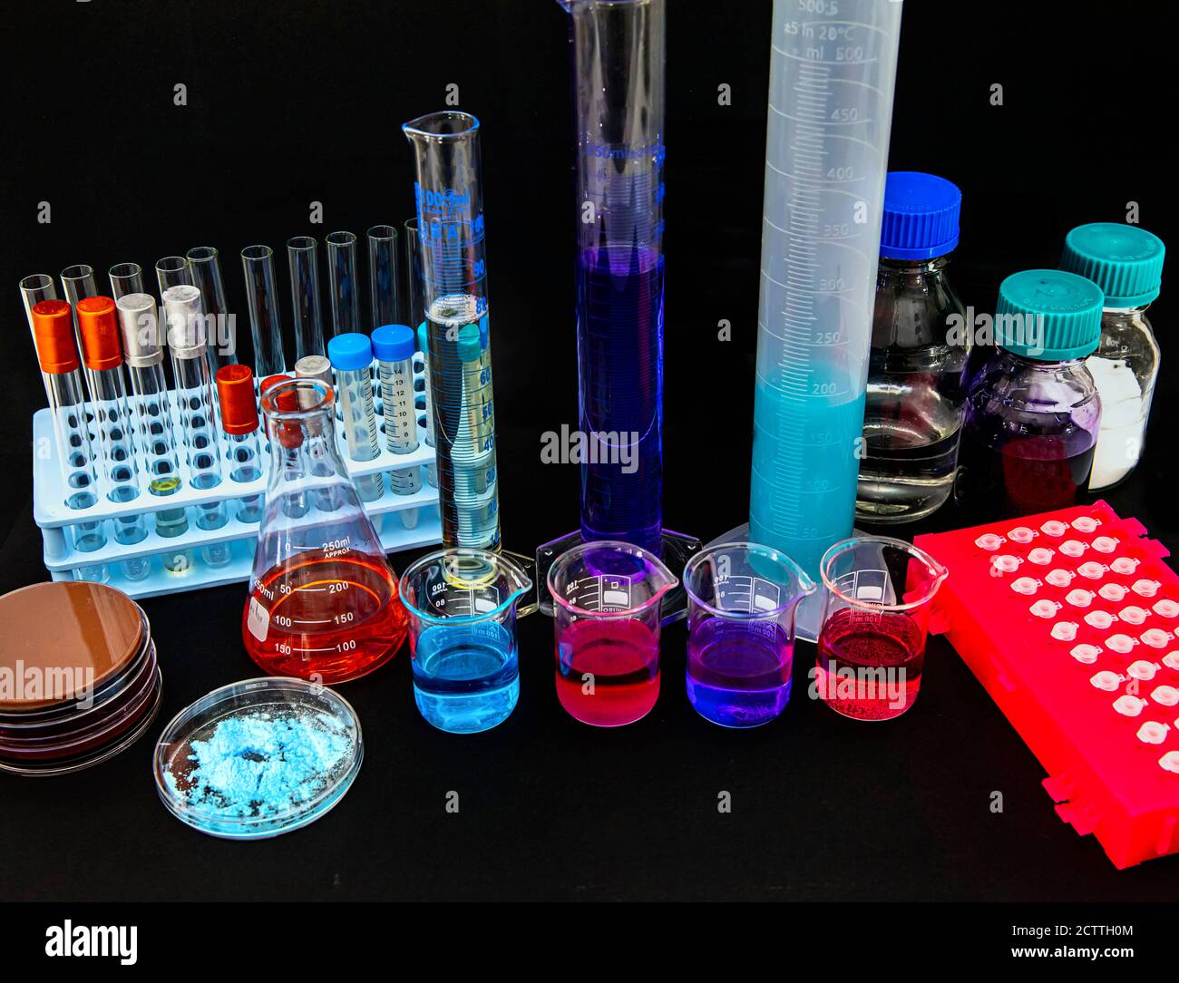 Chemical laboratory glassware with various colored liquids on table ...