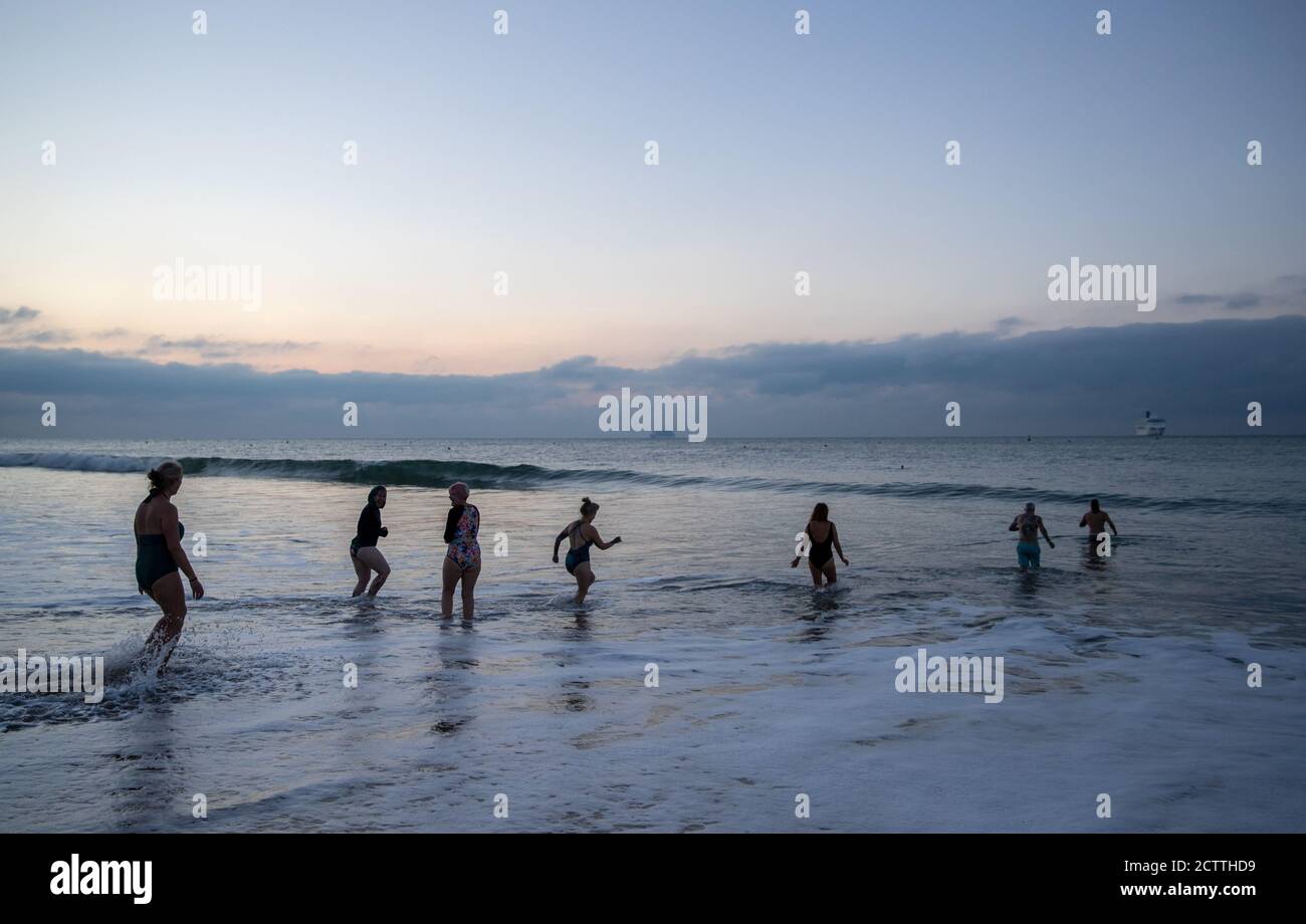 Early morning swimmers take to the sea before sunrise on Boscombe beach ...