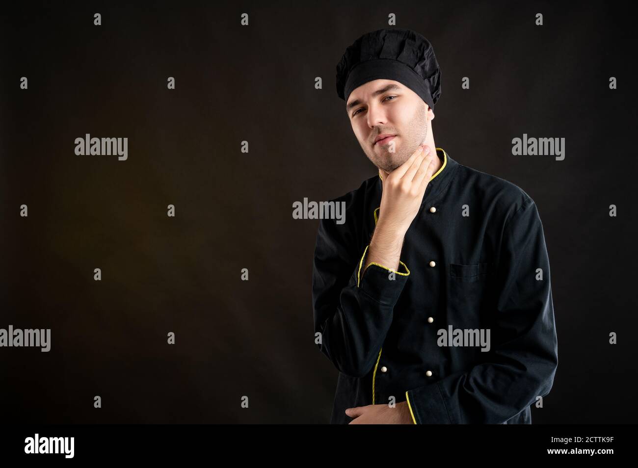 Portrait of young male dressed in a black chef suit with open arms ...