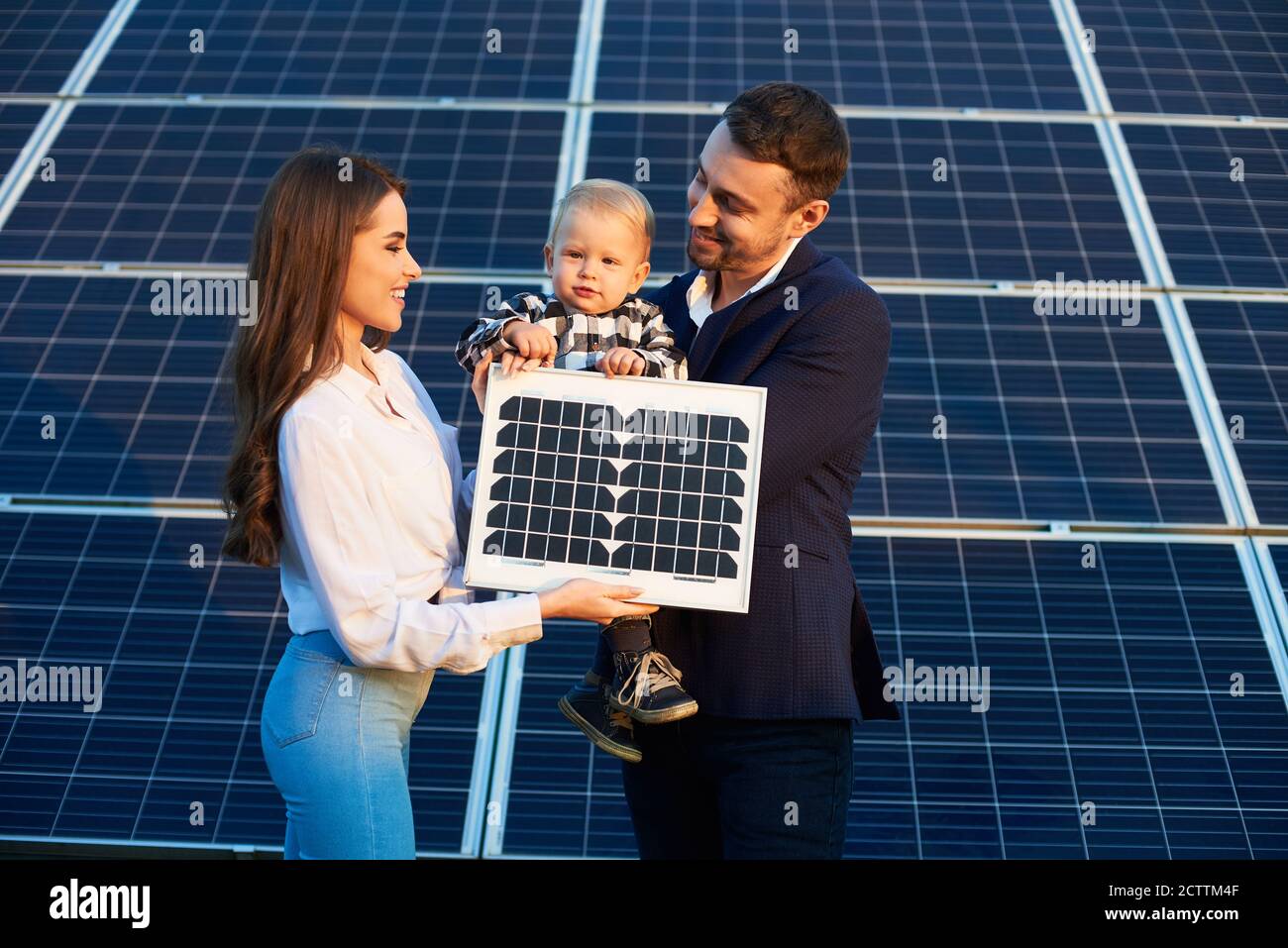 Young happy family on the background of solar panels. A man, woman and ...