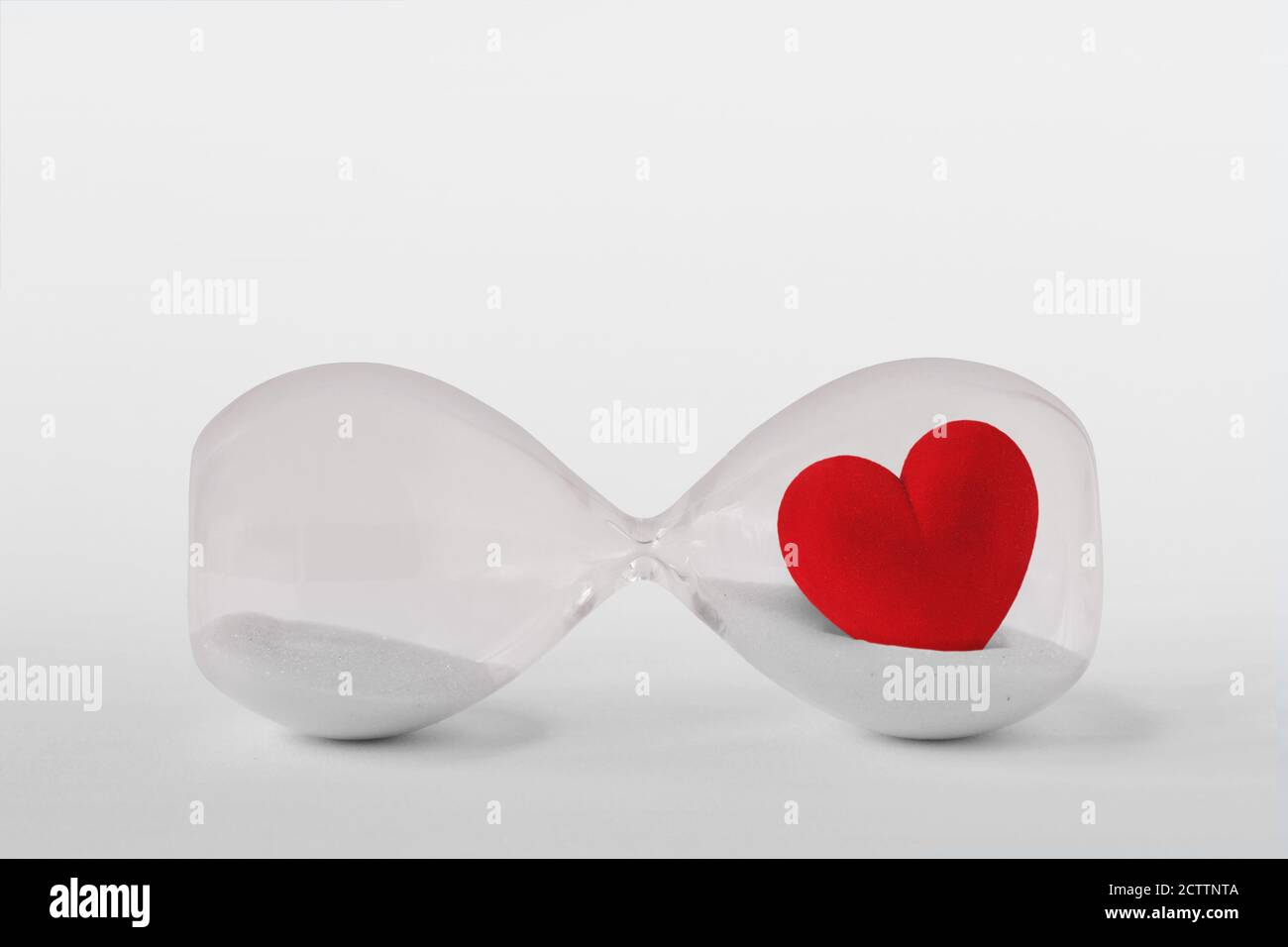 Hourglass with heart lying on white background - Concept of time and ...