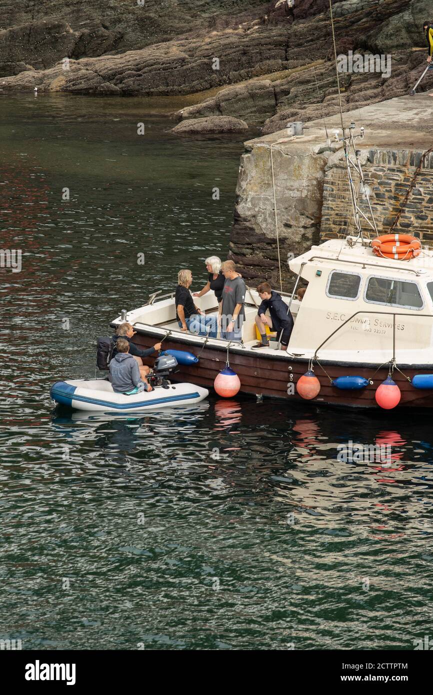 Fisherman lending a hand to a dinghy in Polperro Bay in Cornwall Stock ...