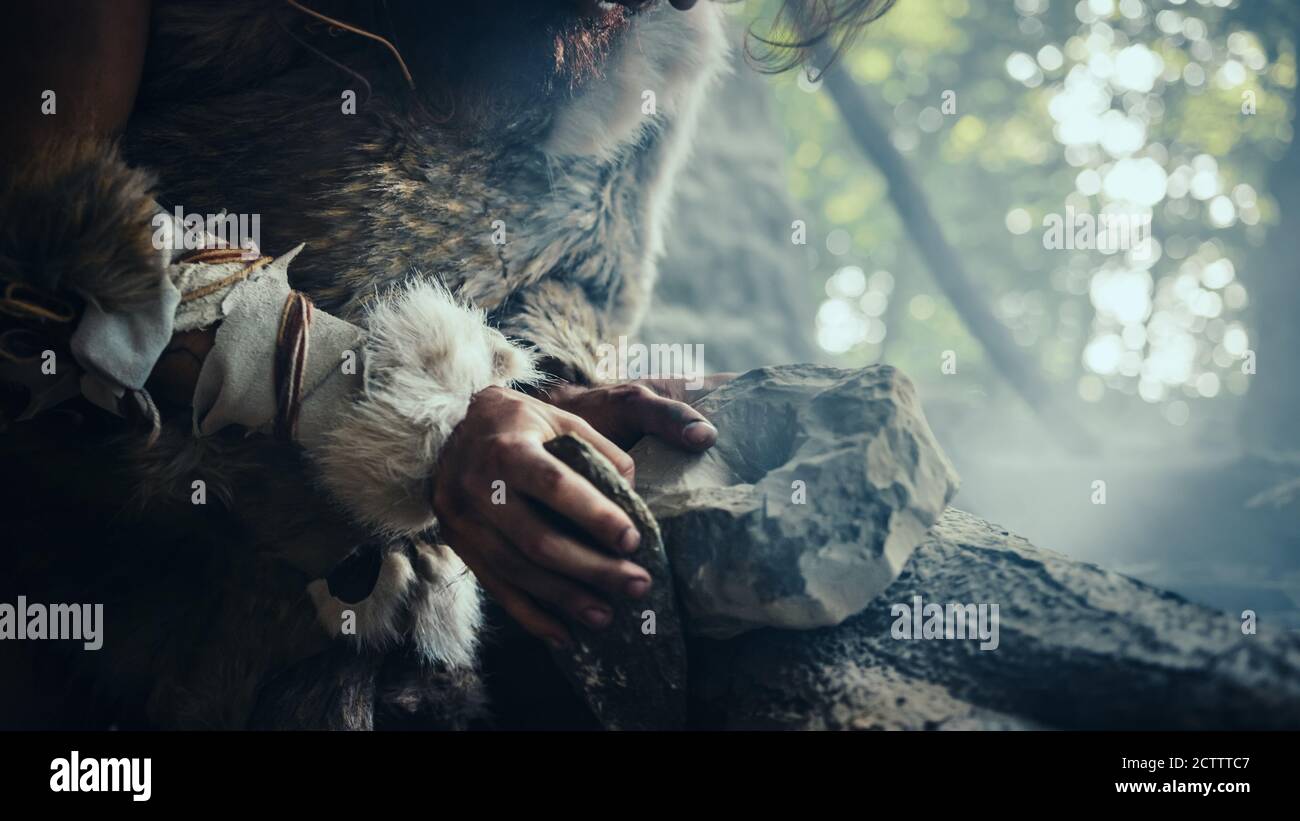 Closeup Shot of Primeval Caveman in Animal Skin Hits Rock with Sharp ...