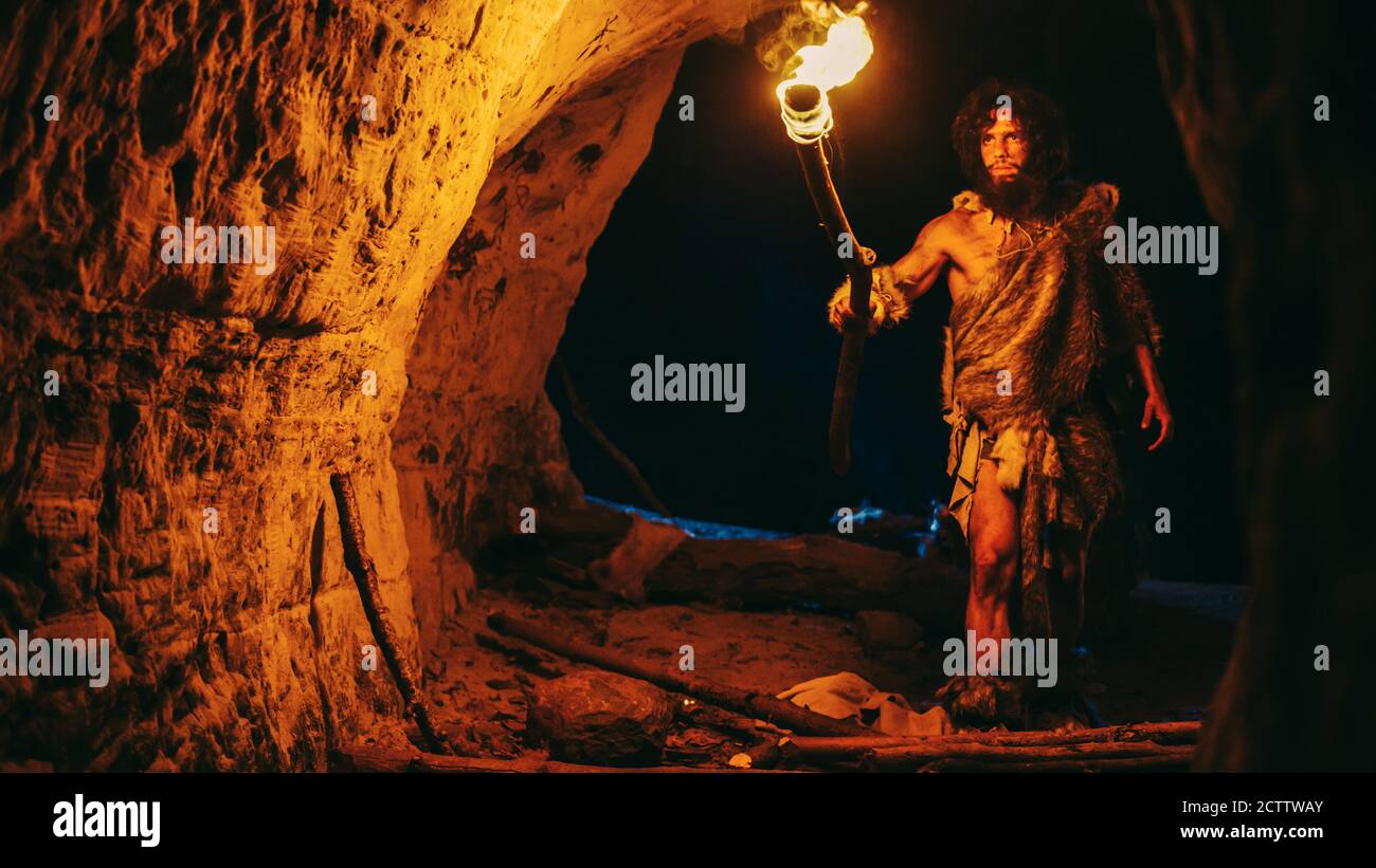 Primeval Caveman Wearing Animal Skin Exploring Cave At Night, Holding ...
