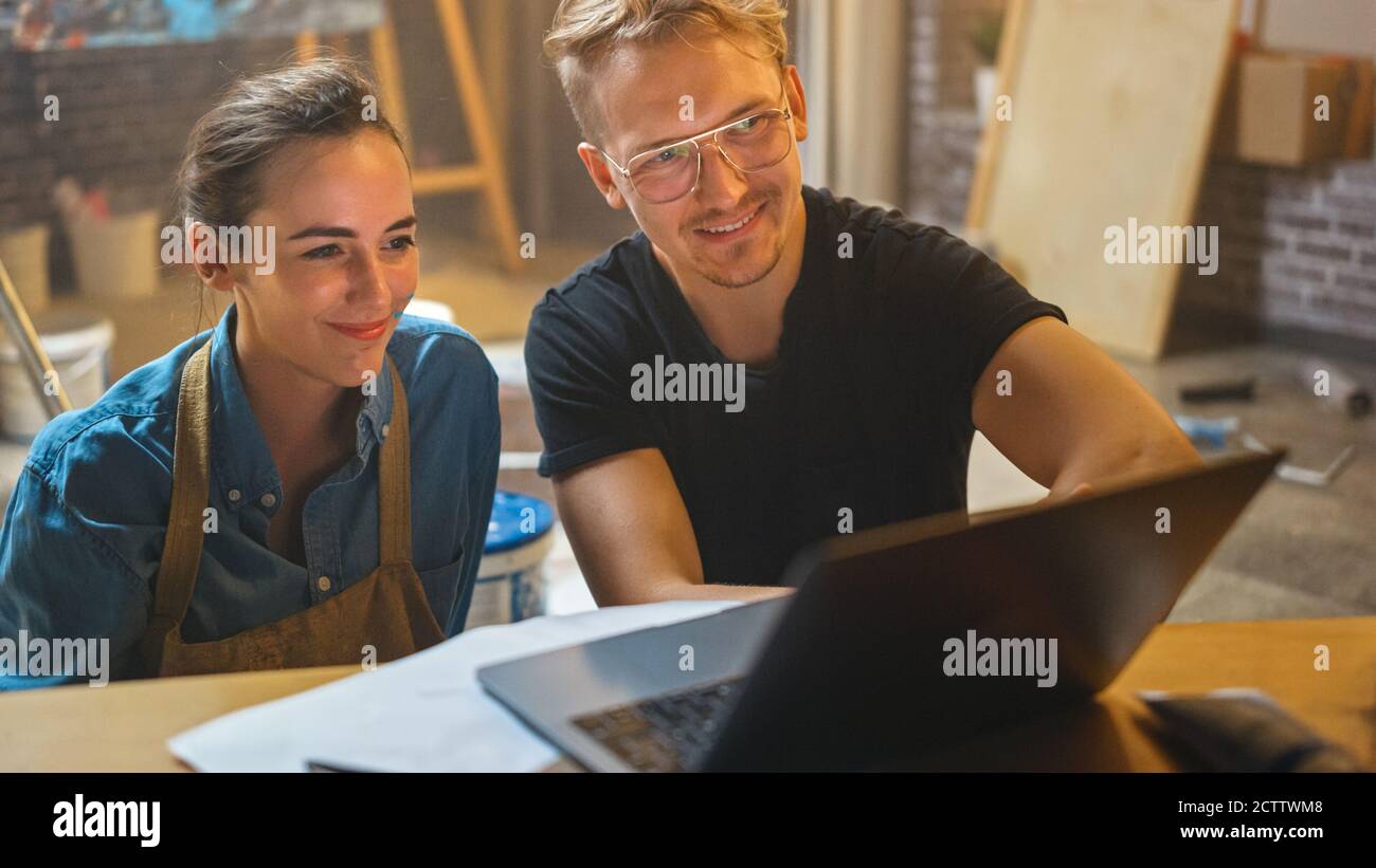 Couple of Artists Sitting in their Studio Use Laptop Computer, Working ...