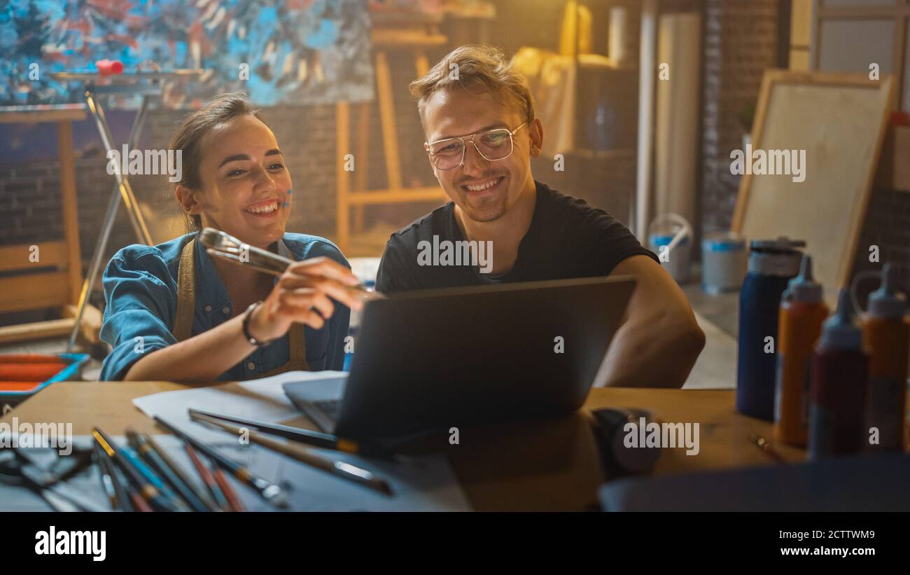 Couple of Artists Sitting in their Studio Use Laptop Computer, Working ...