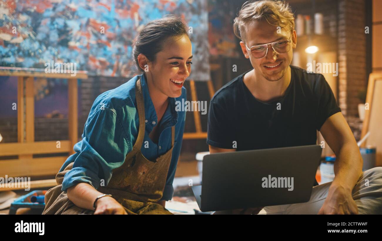 Couple of Artists Sitting in their Studio Use Laptop Computer, Working ...
