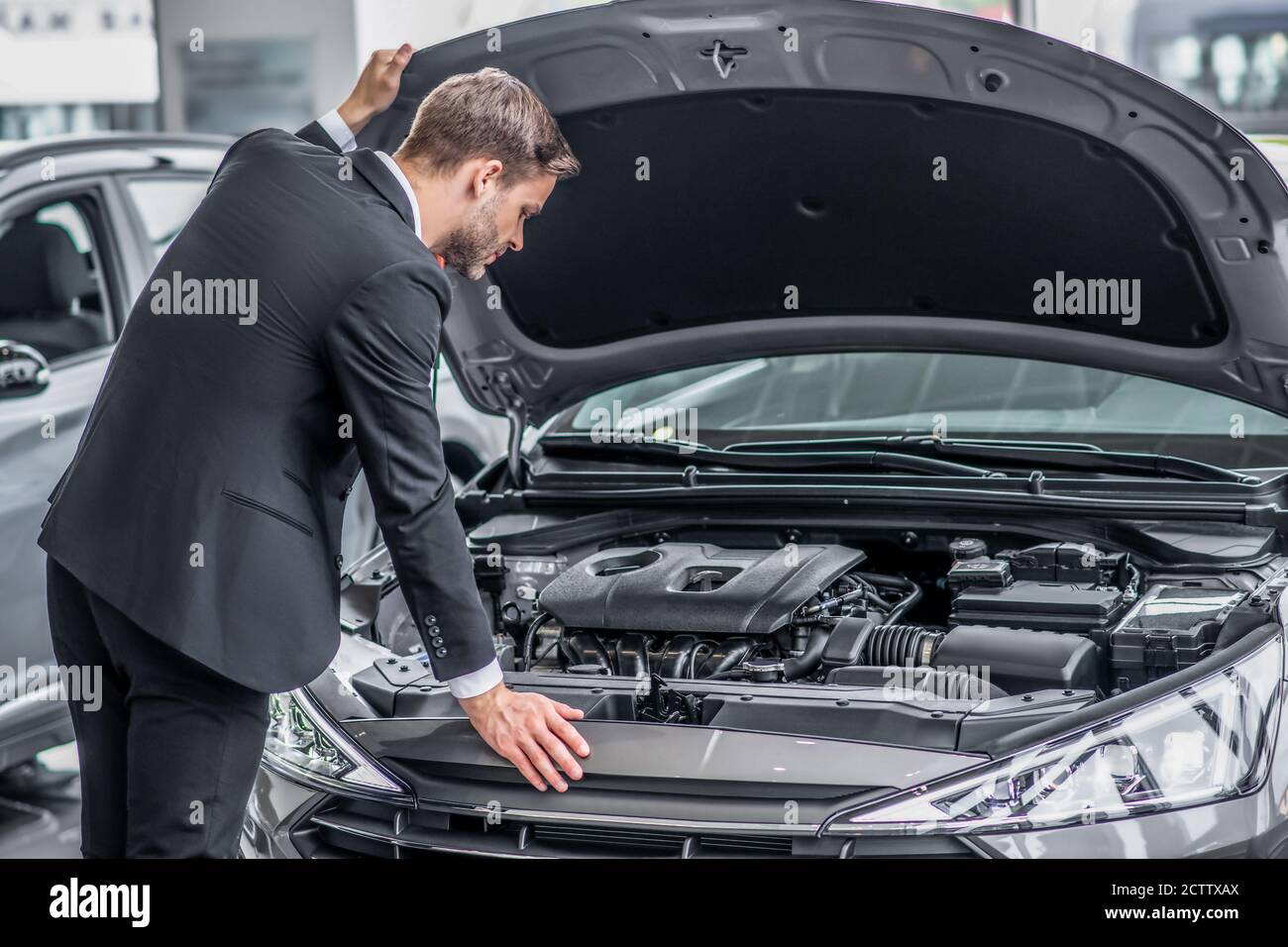 Man in a black suit looking at the car engine Stock Photo - Alamy