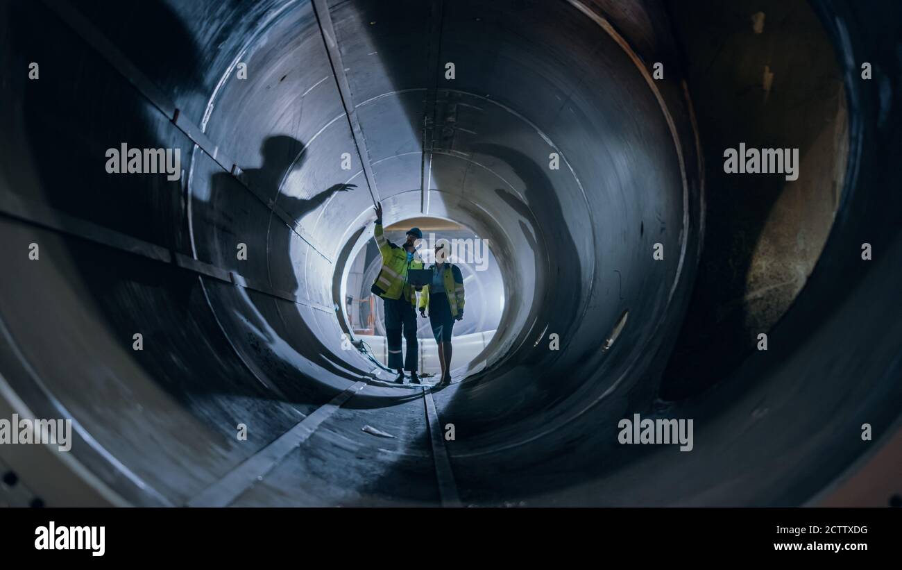 Two Heavy Industry Engineers Walking Inside Pipe, Use Laptop, Have ...