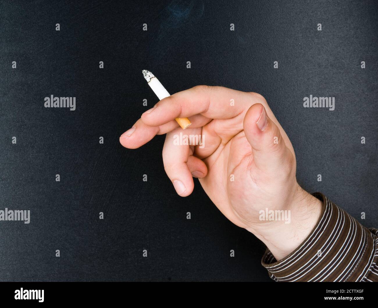 Cigarette in male fingers on black background Stock Photo - Alamy