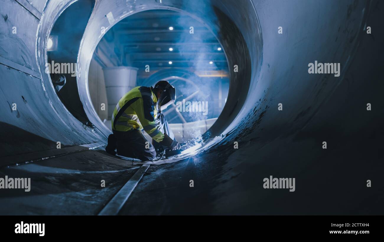Professional Heavy Industry Welder Working Inside Pipe, Wears Helmet ...