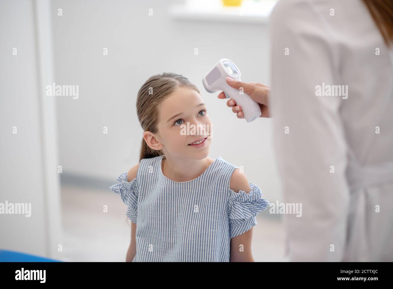 Doctor checking temperature of her small patient Stock Photo - Alamy