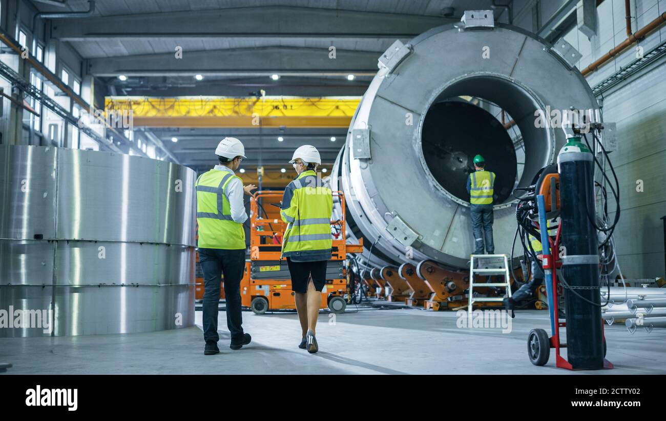 Two Heavy Industry Engineers Walk Through Pipe Manufacturing Factory ...