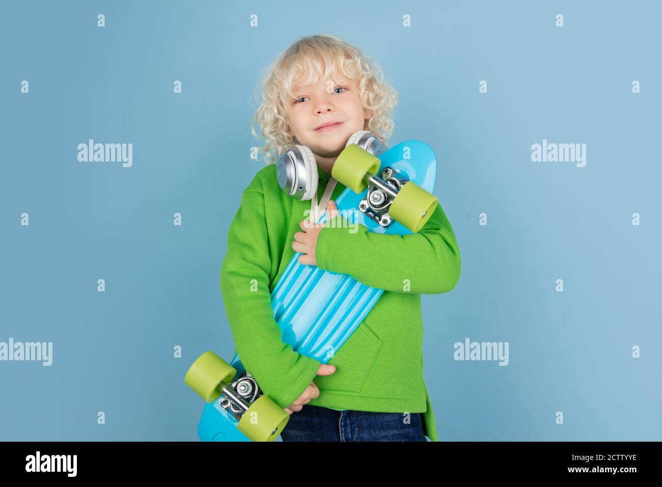 Skater boy. Portrait of beautiful caucasian little boy isolated on blue ...