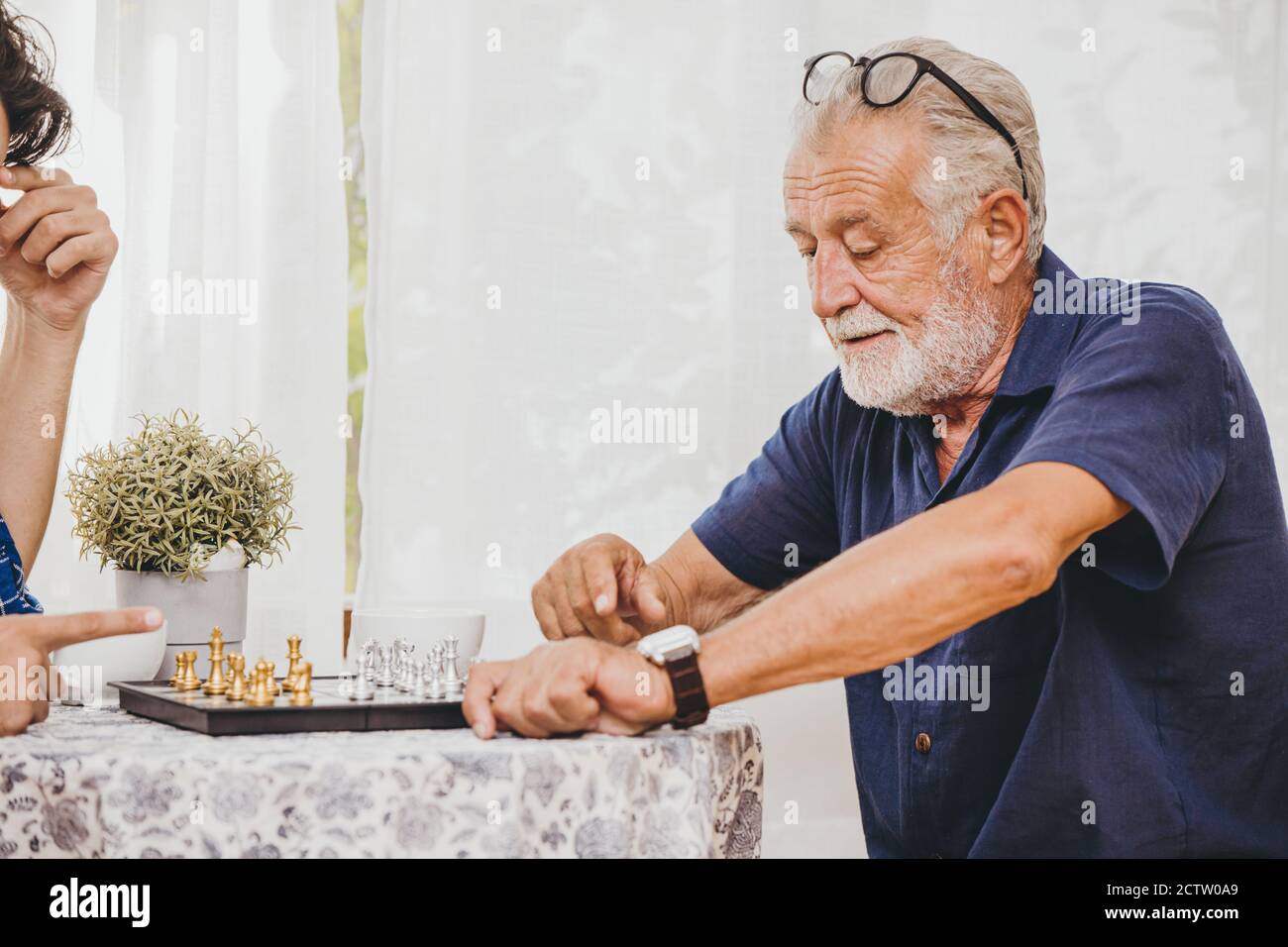 Old man playing Chess board game at home for training brain memory and ...