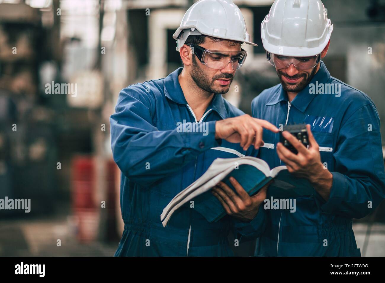 Engineer service team looking at machine service manual text book ...