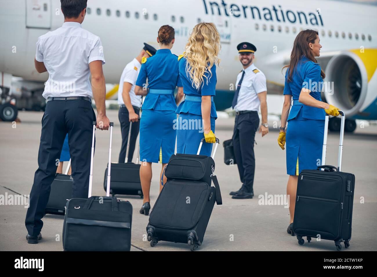 Airline workers walking down the airfield and heading to plane Stock ...