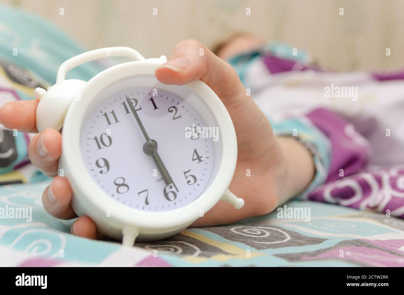 female hand holding white alarm clock lying in bed, early rise Stock ...