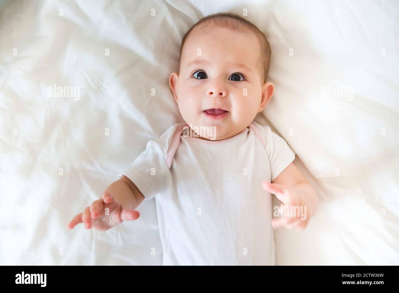 Happy amazed baby girl in white clothes pulling hands to mom. On white ...