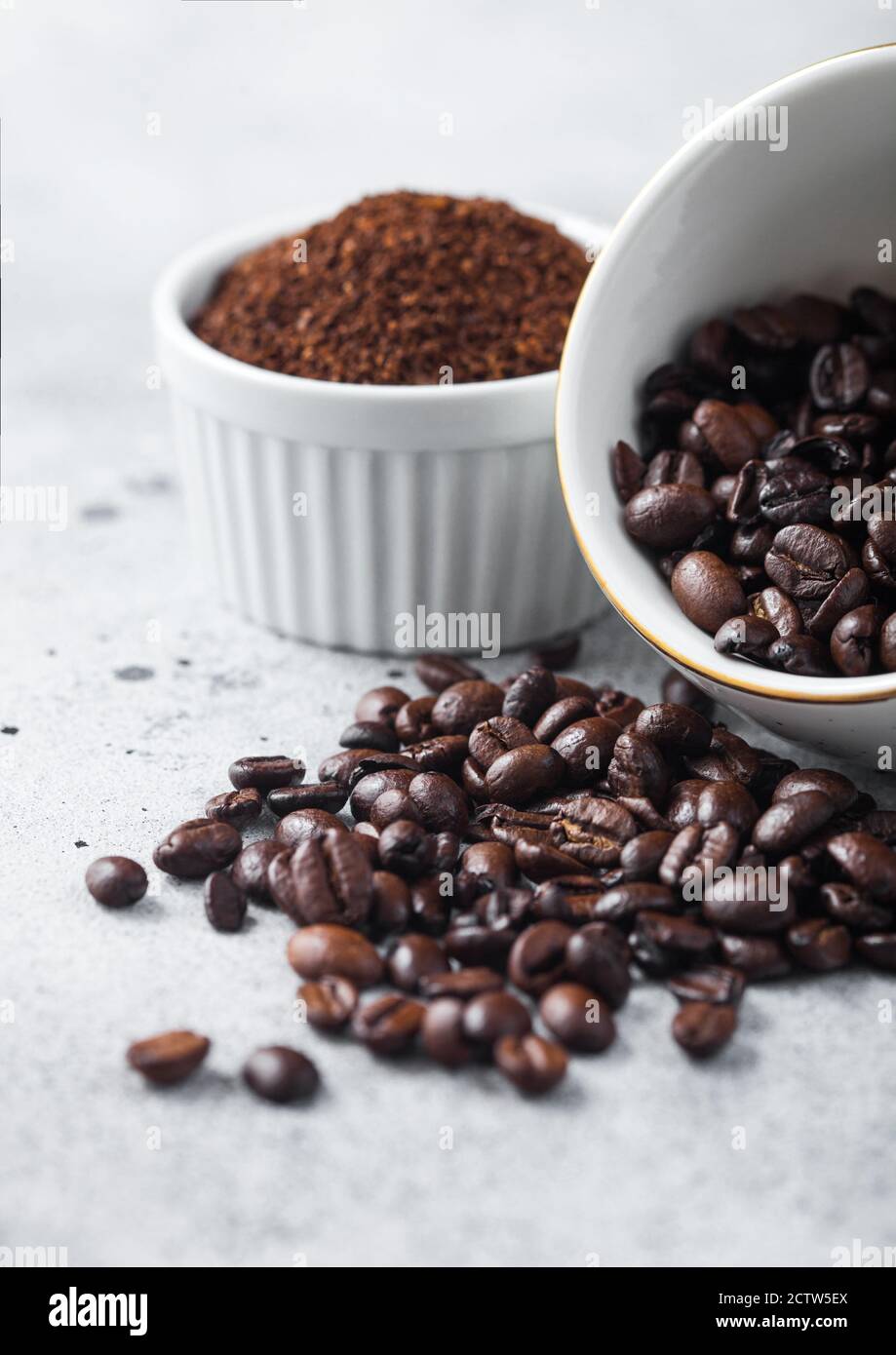 Two bowls with fresh raw coffee beans and powder on light table ...