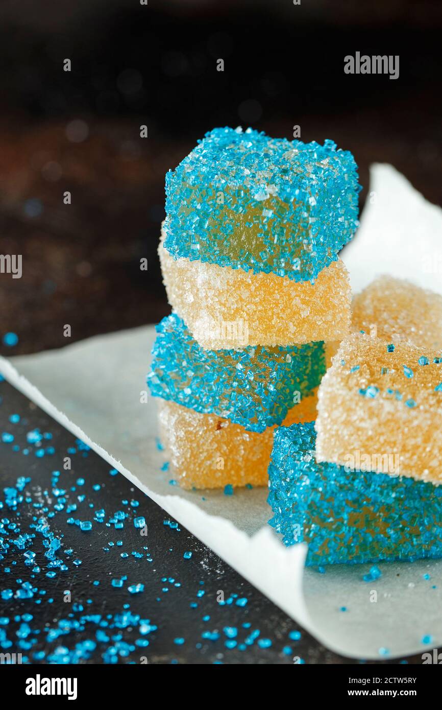 Homemade yellow and blue marmalade candy in sugar sweet sand on dark ...