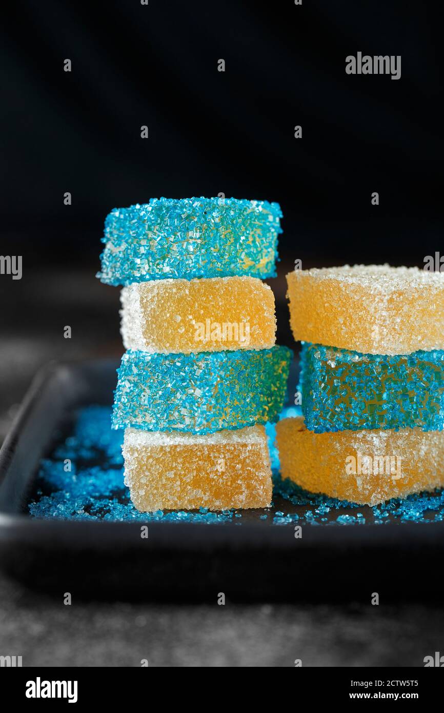 Homemade yellow and blue marmalade candy in sugar sweet sand on dark ...