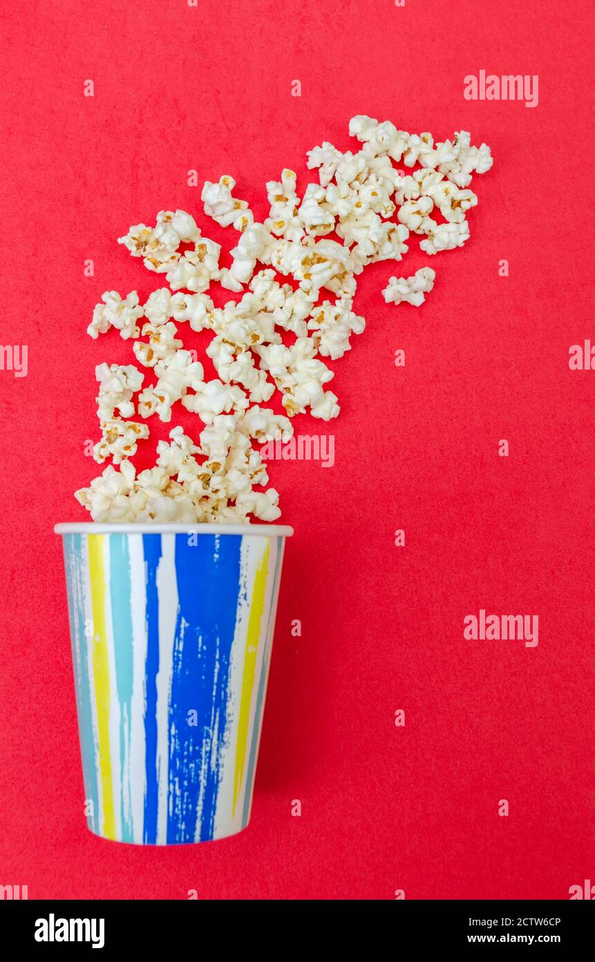 Spilled popcorn from a paper Cup on a red background, top view, copy ...