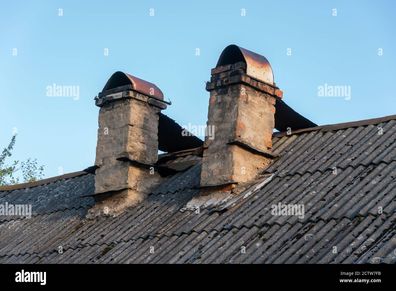 Two chimneys on the roof of the house close up against the blue sky ...