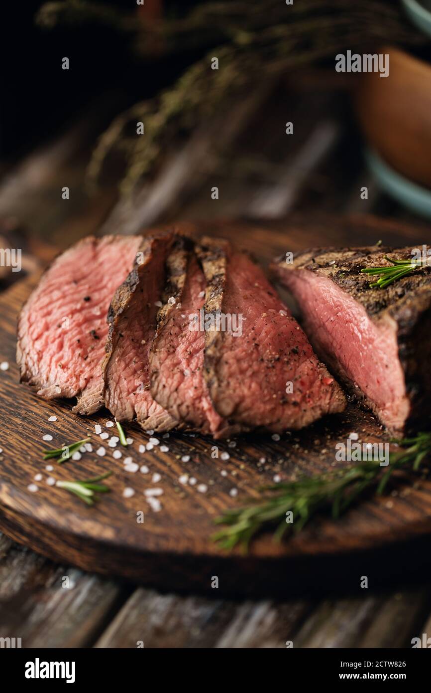 Juicy medium Beef Rib Eye steak slices on wooden board with herbs ...