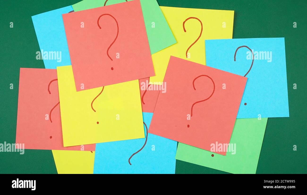 Lots of colorful note sheets with question marks on a green background ...