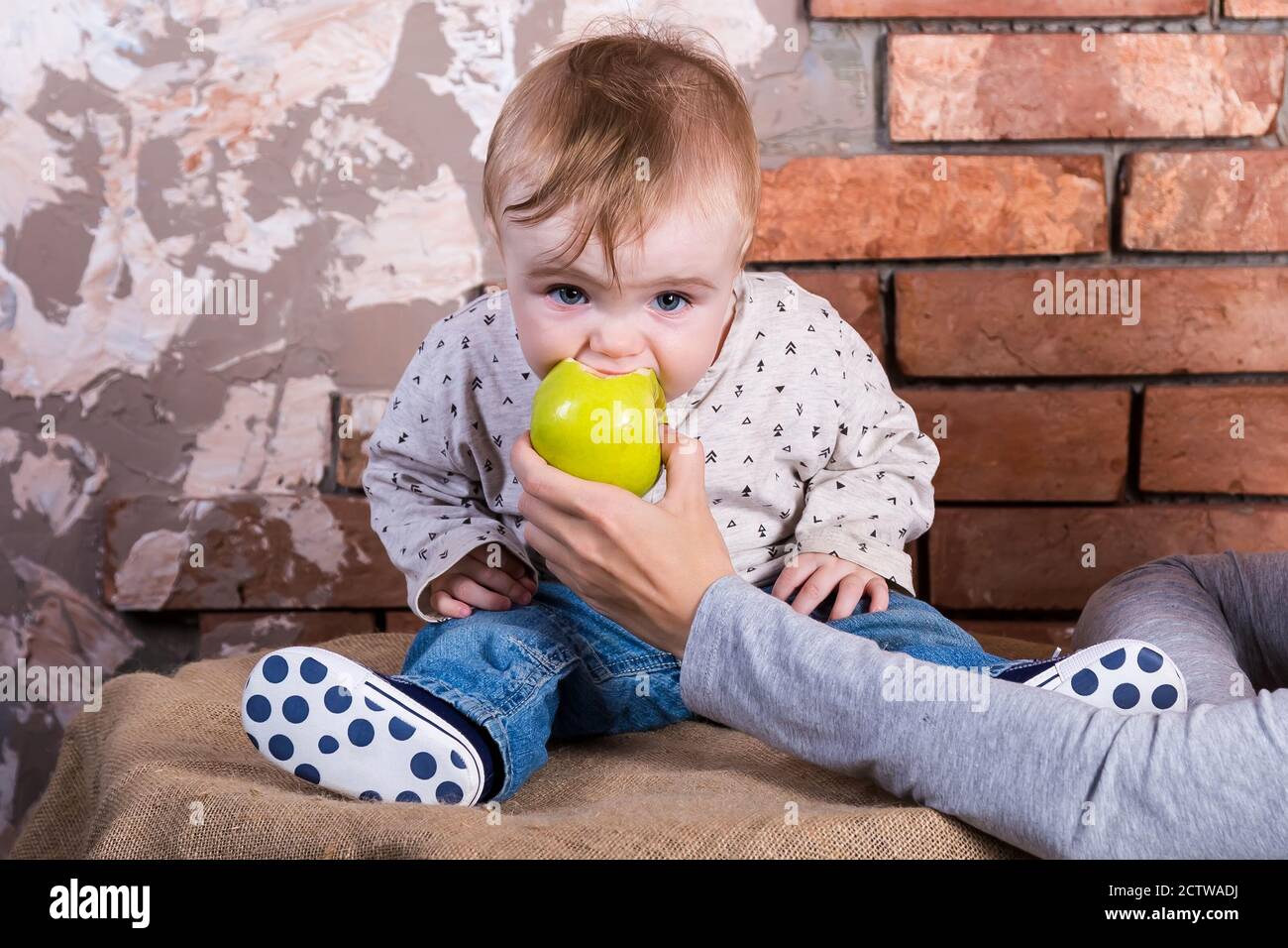 One year old child sits on a barrel against the background of a red ...