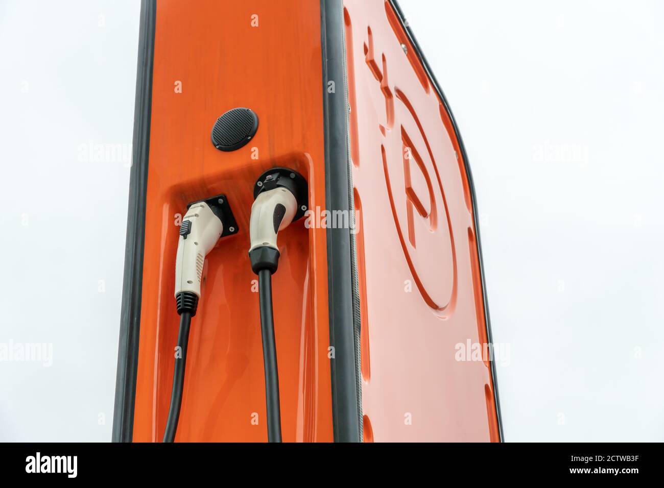 Orange charging station for electric vehicles against a gray-white sky ...