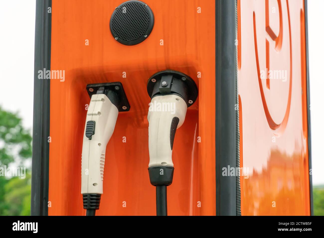 Orange charging station for electric vehicles against a gray-white sky ...